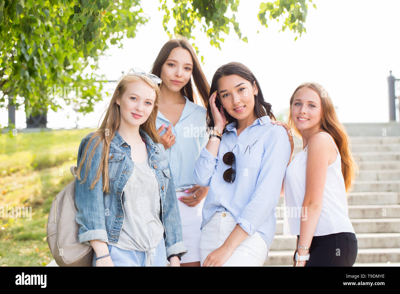 Portrait of four happy beautiful student girls on nature background in ...
