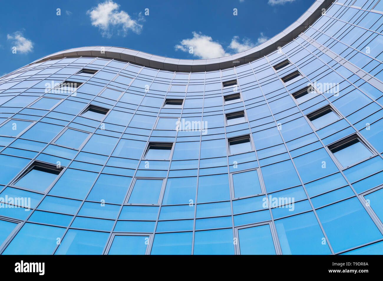 Blue glass tall building against the sky with clouds, view from below ...