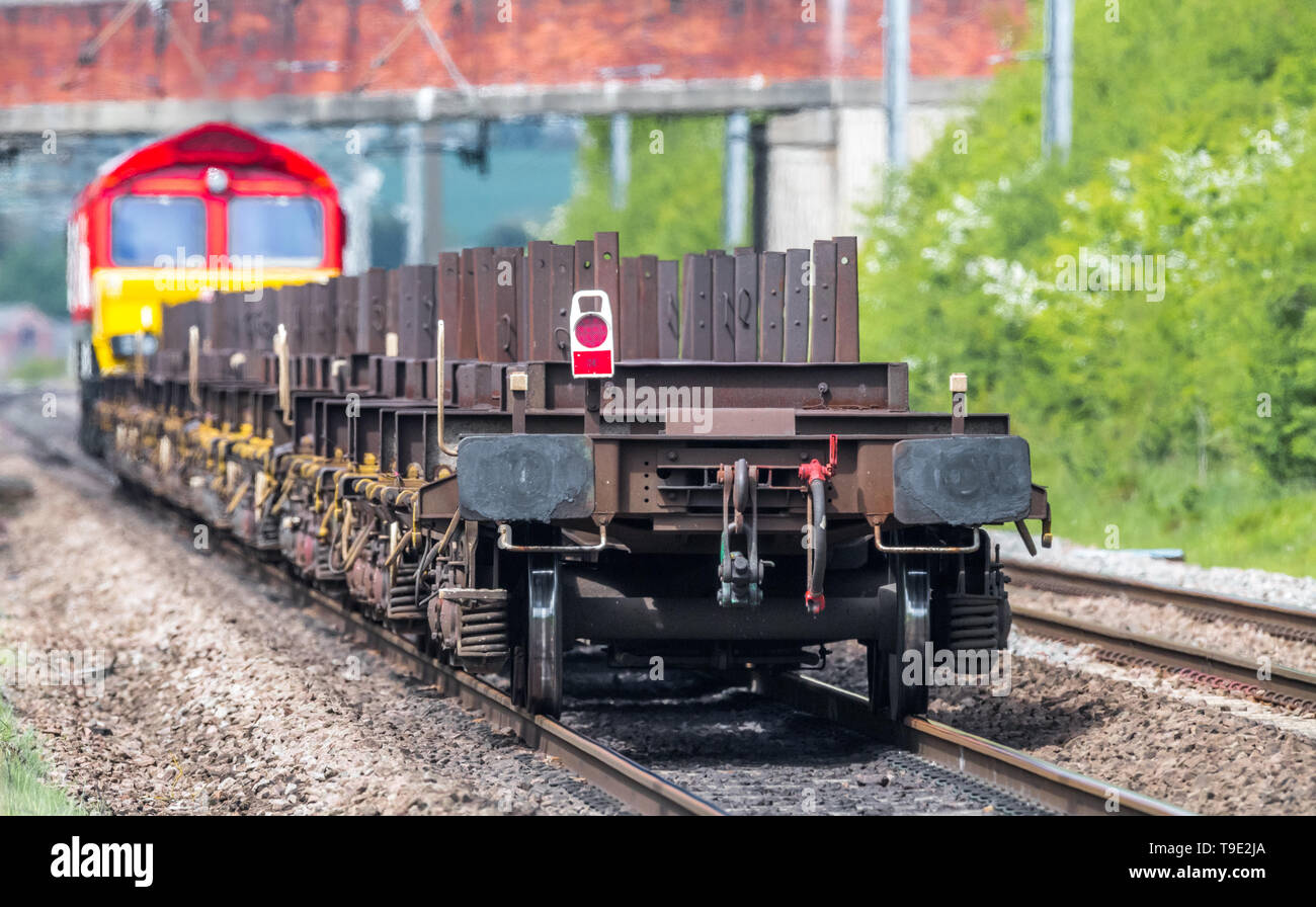 Freight train pulling empty trailers for carrying steel rail tracks ...