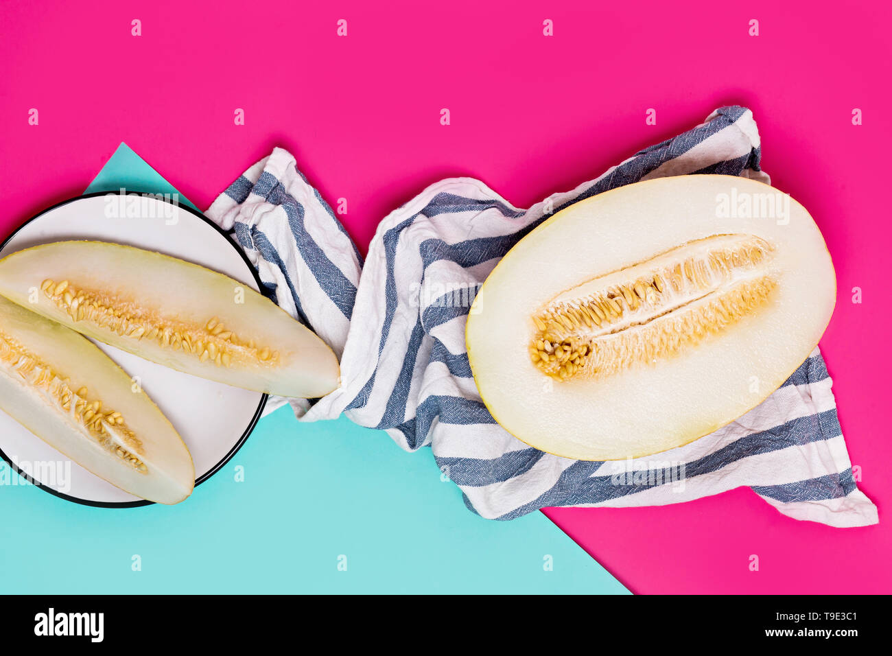 Flat lay of fresh melons sliced on colorful blue and pink background ...