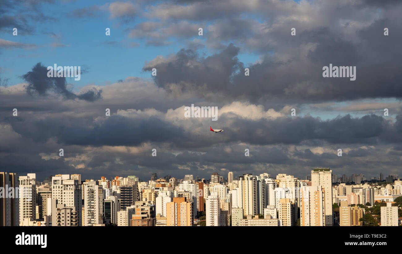 Airplane flying over the city Stock Photo - Alamy