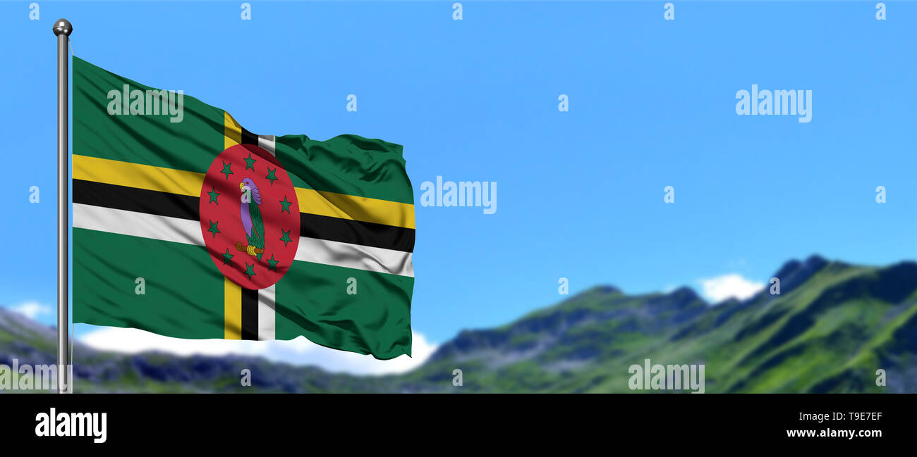 Dominica flag waving in the blue sky with green fields at mountain peak ...