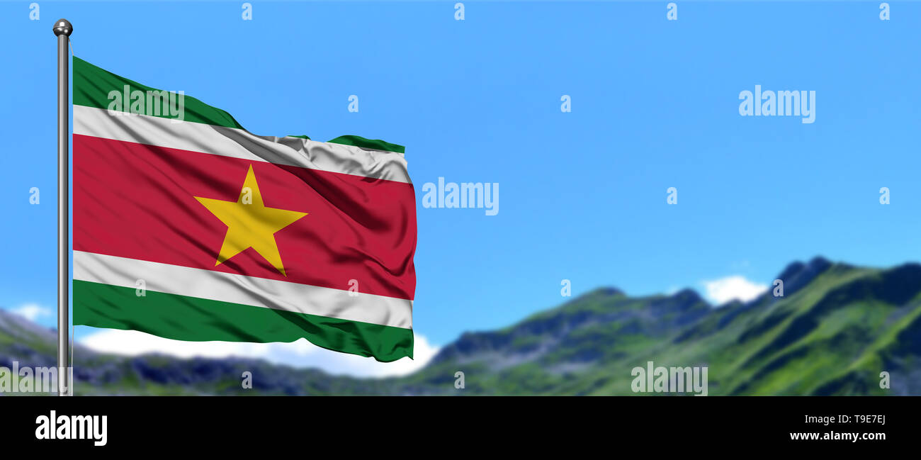 Suriname flag waving in the blue sky with green fields at mountain peak ...