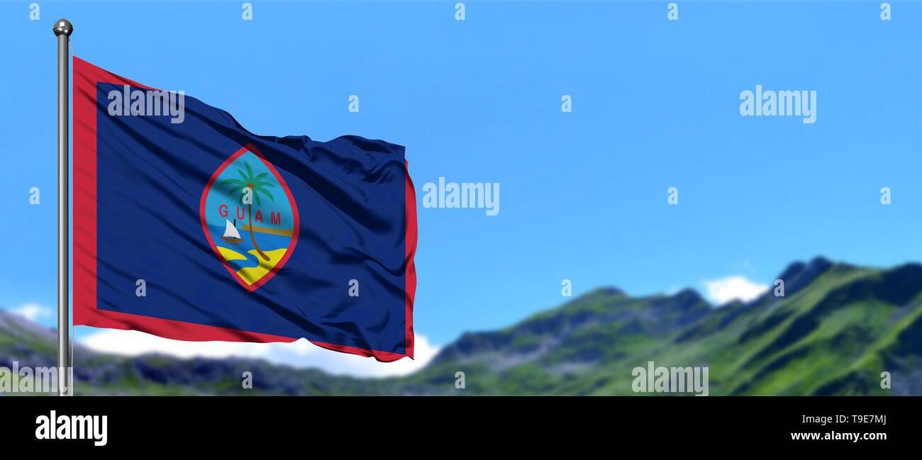 Guam flag waving in the blue sky with green fields at mountain peak ...