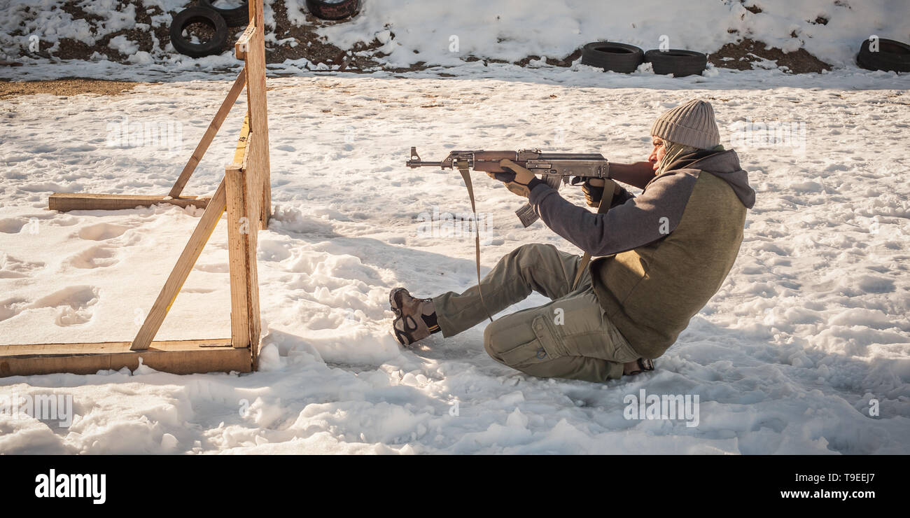Instructor demonstrate body position of combat rifle shooting at winter ...