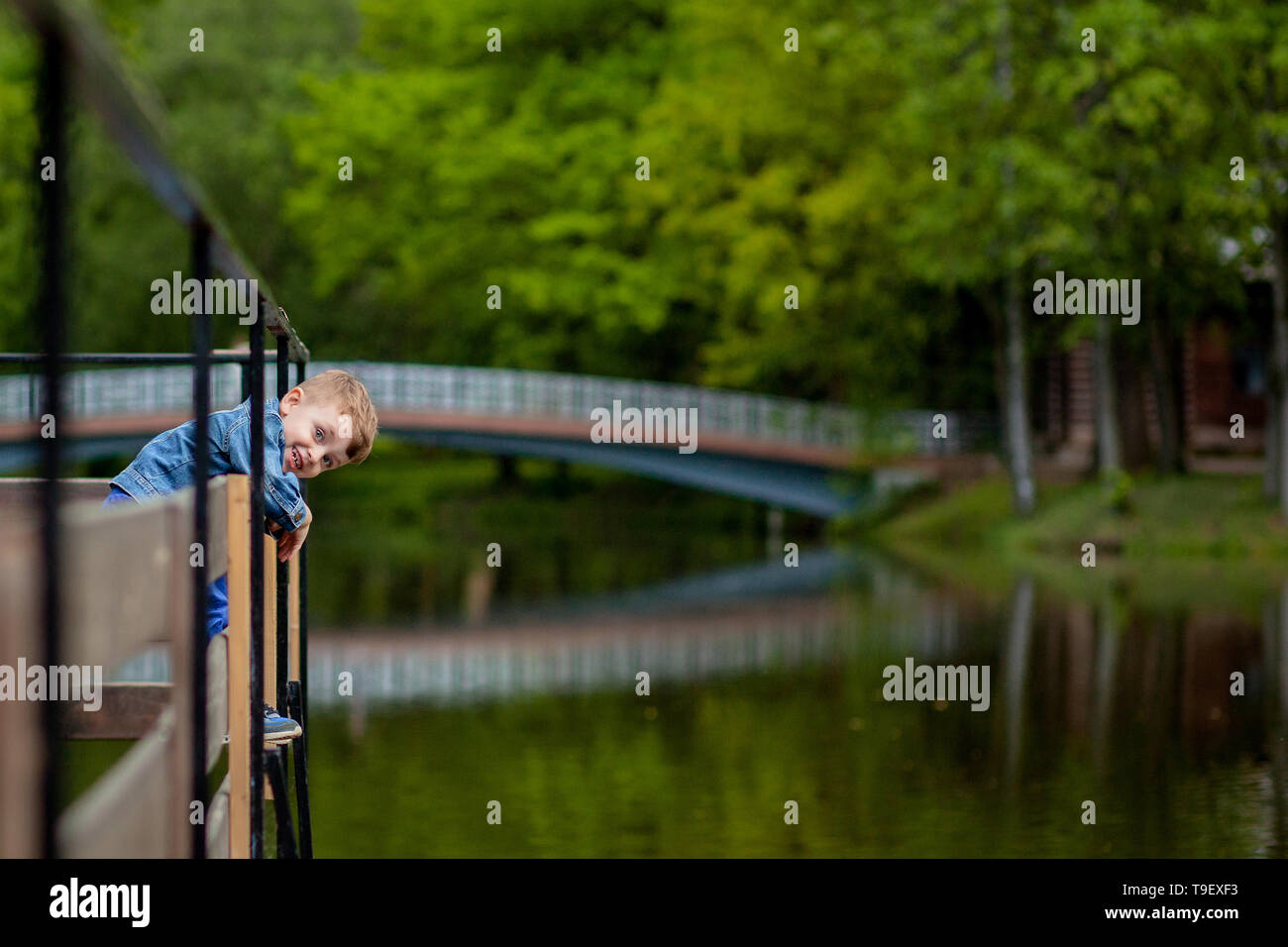 A little boy climbs a bridge railing in the park. The threat of ...