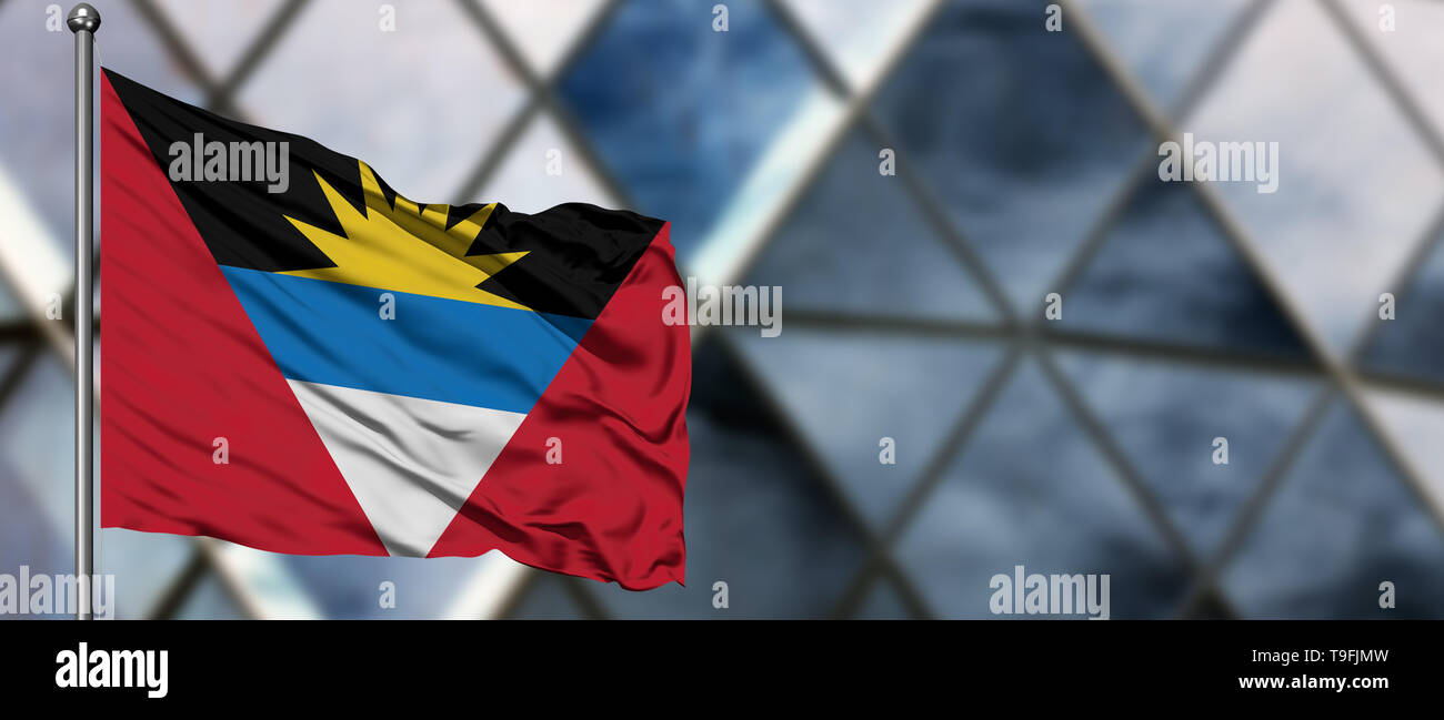Antigua and Barbuda flag waving in the wind against blurred modern ...