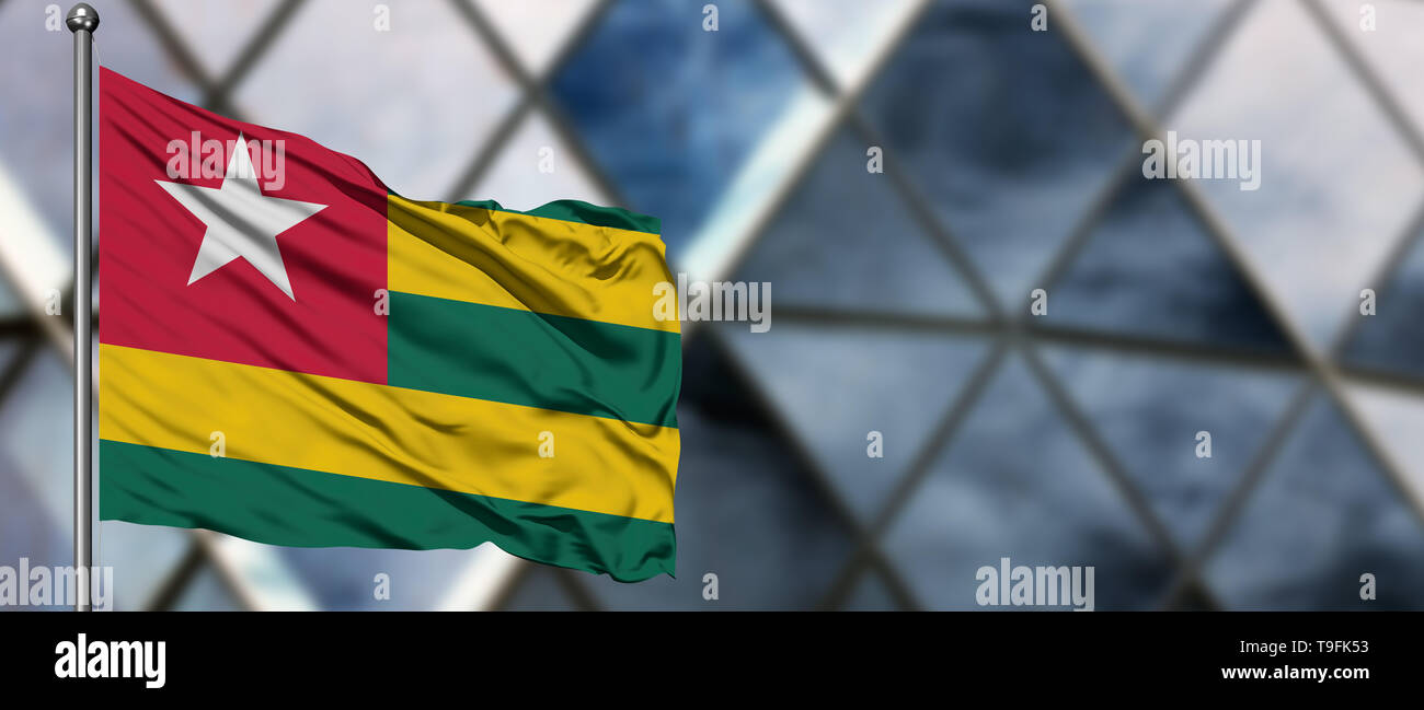 Togo flag waving in the wind against blurred modern building. Business ...