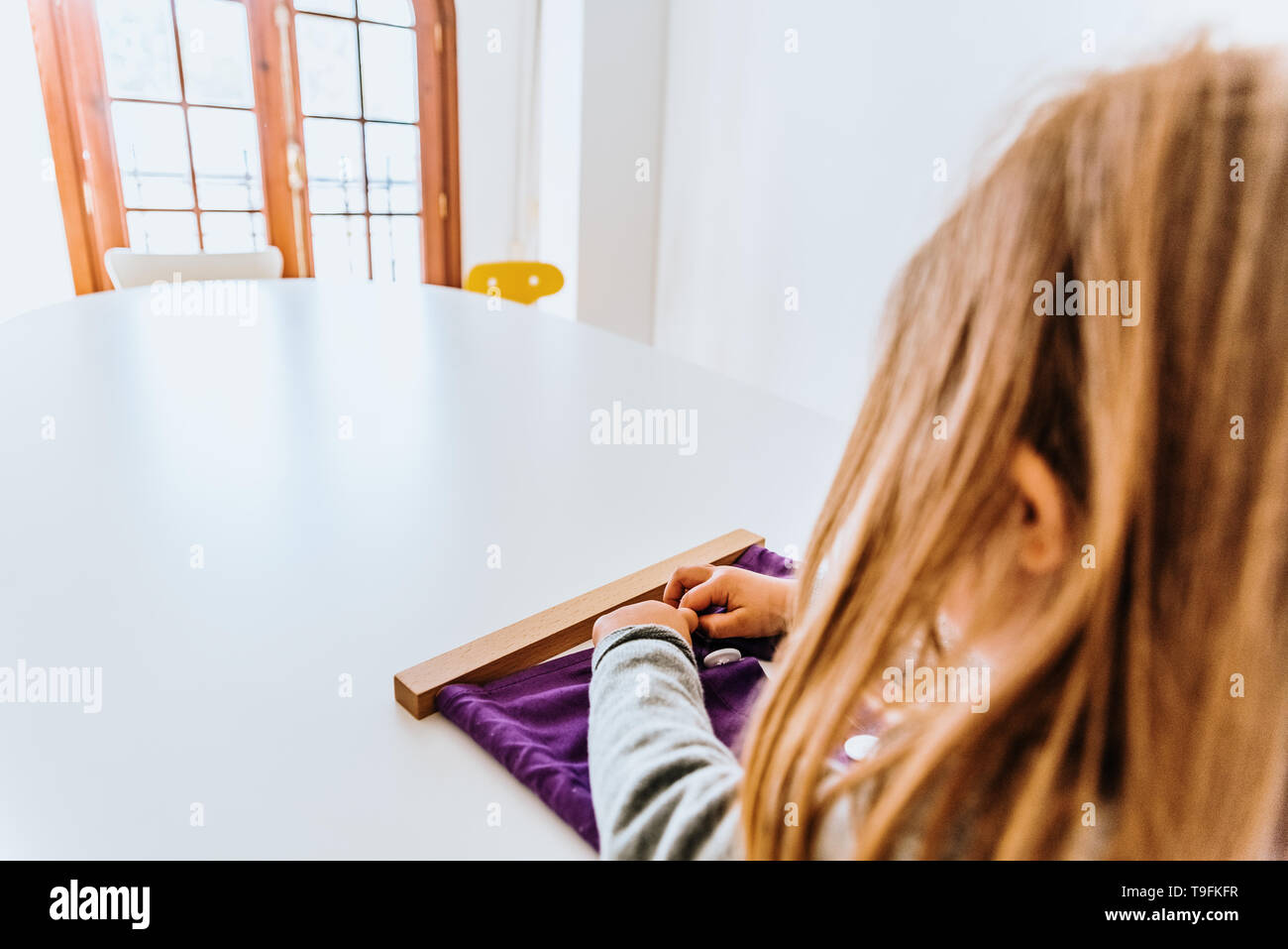 Girl buttoning a montessori frame to develop the dexterity of her ...