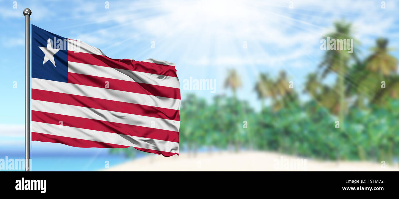 Waving Liberia flag in the sunny blue sky with summer beach background ...