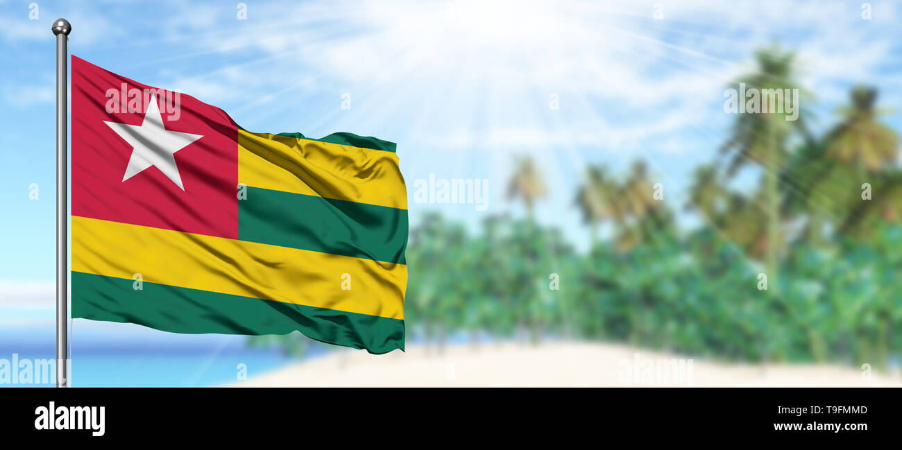 Waving Togo flag in the sunny blue sky with summer beach background ...