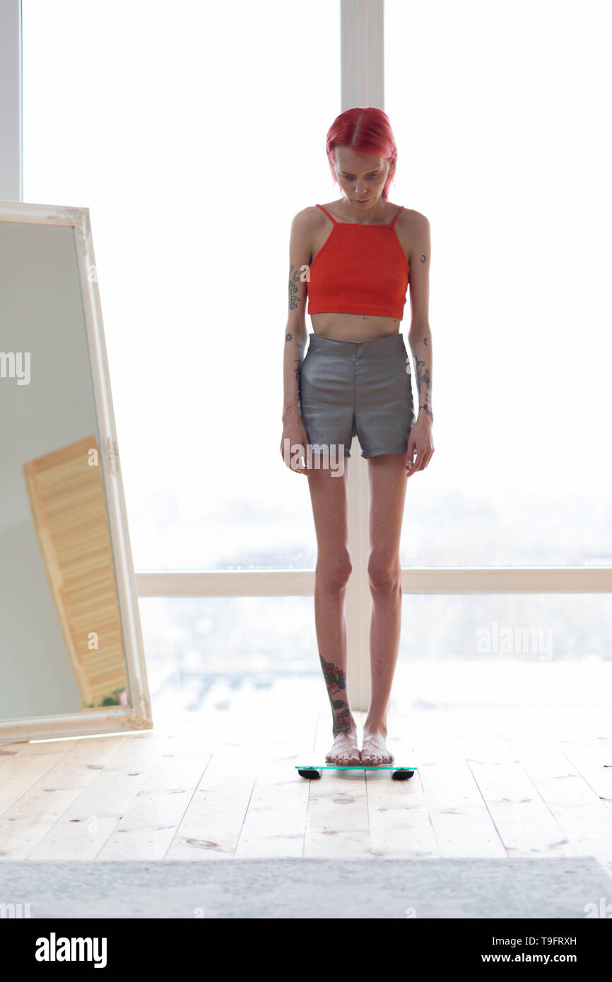 Woman wearing shorts and top standing on weight scales Stock Photo - Alamy