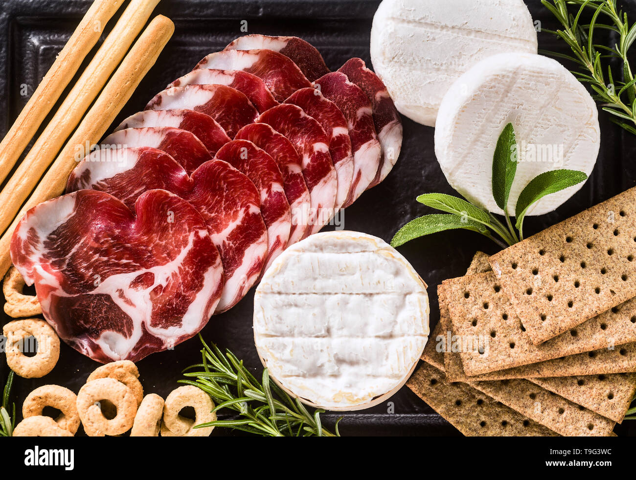 cold cuts and cheese are served on a tray on a table with white wine ...