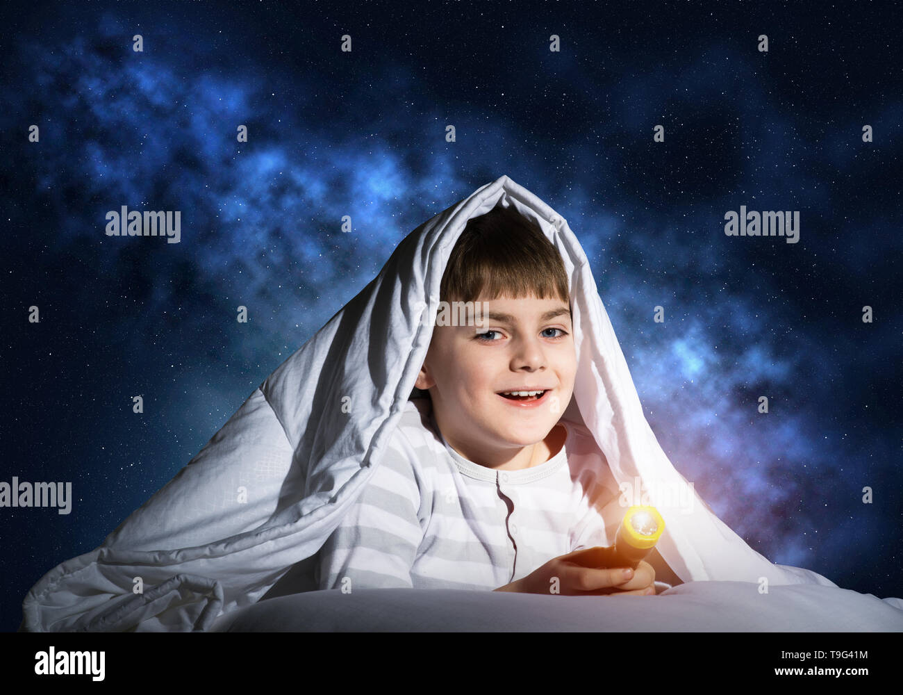 Happy child with flashlight hiding under blanket Stock Photo - Alamy