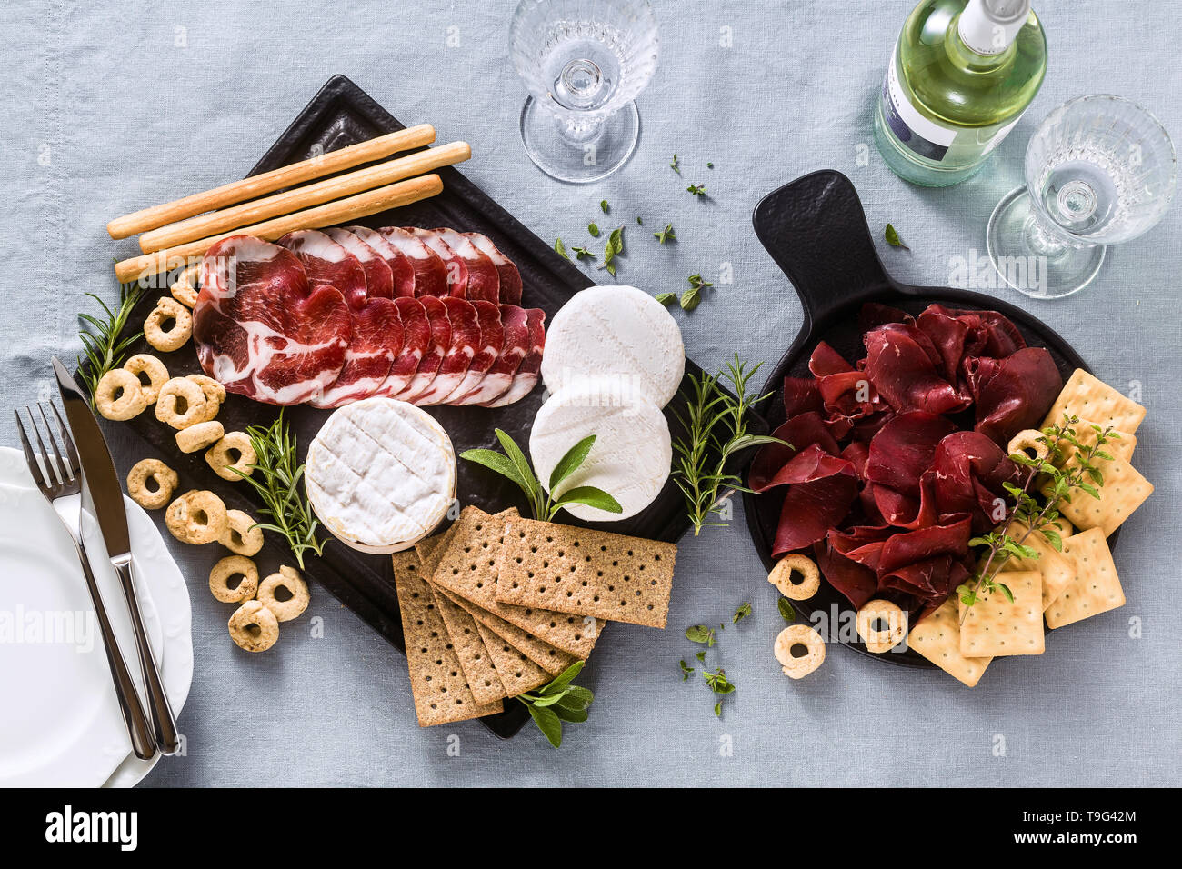 cold cuts and cheese are served on a tray on a table with white wine ...