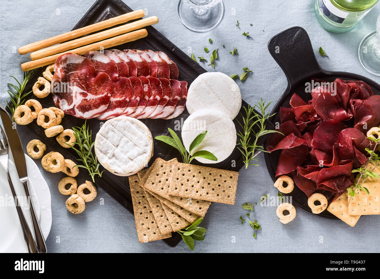 cold cuts and cheese are served on a tray on a table with white wine ...