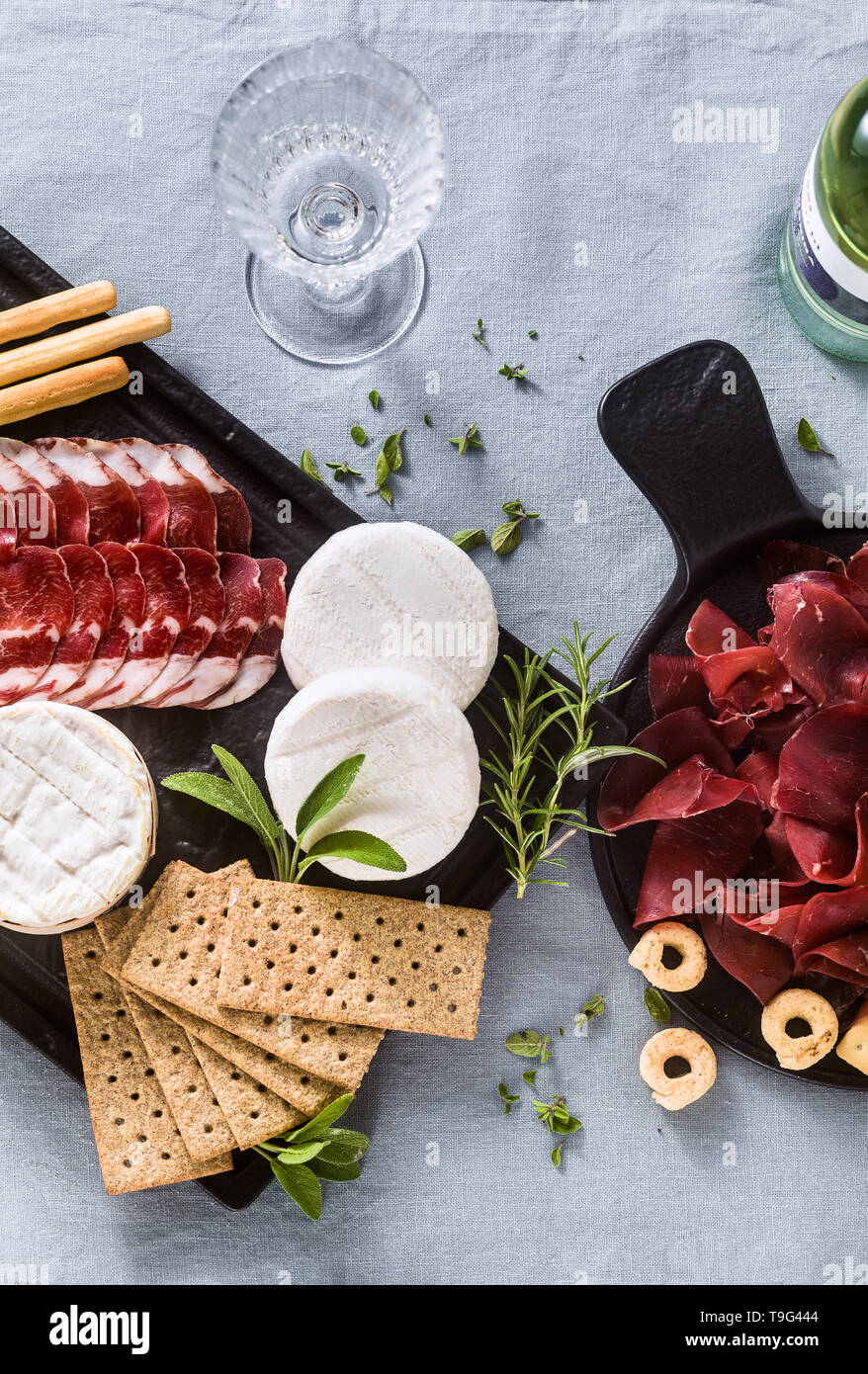 cold cuts and cheese are served on a tray on a table with white wine ...
