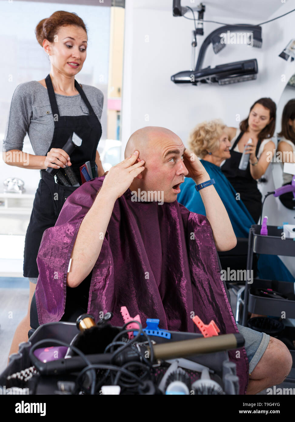 Portrait of shocked bald man sitting in barber chair with apologetic ...