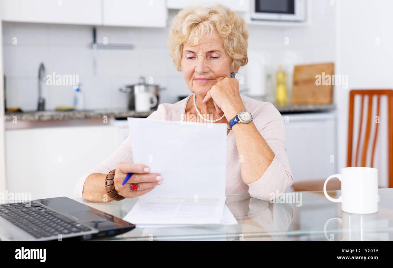 Mature woman filling up documents at kitchen table Stock Photo - Alamy