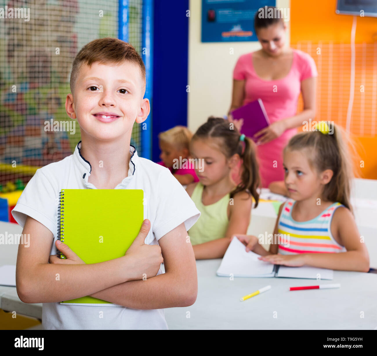 Glad boy pupil standing in elementary school class with textbook in ...
