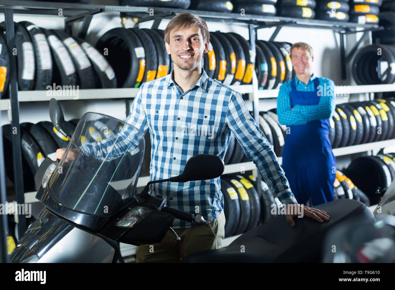 Cheerful man customer holding his motorcycle at maintenance point Stock ...