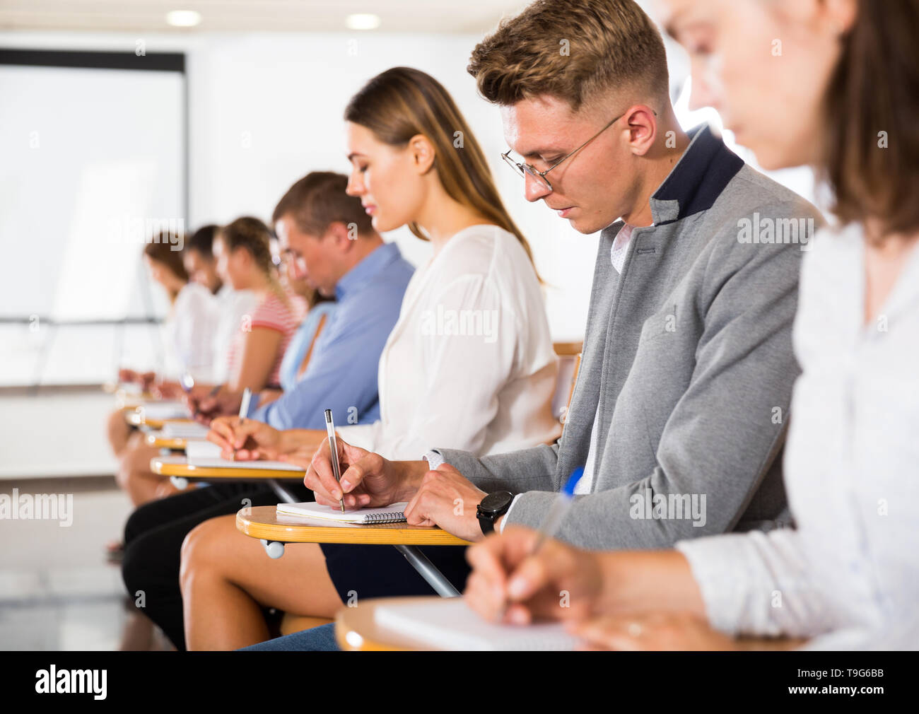 Side view of student group working on lecture in classroom, making ...