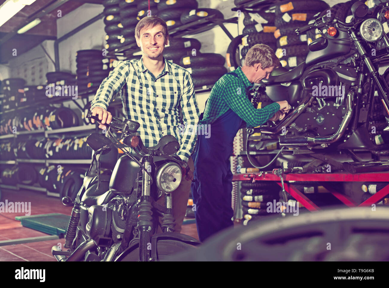 Laughing man customer holding his motorcycle at maintenance point Stock ...