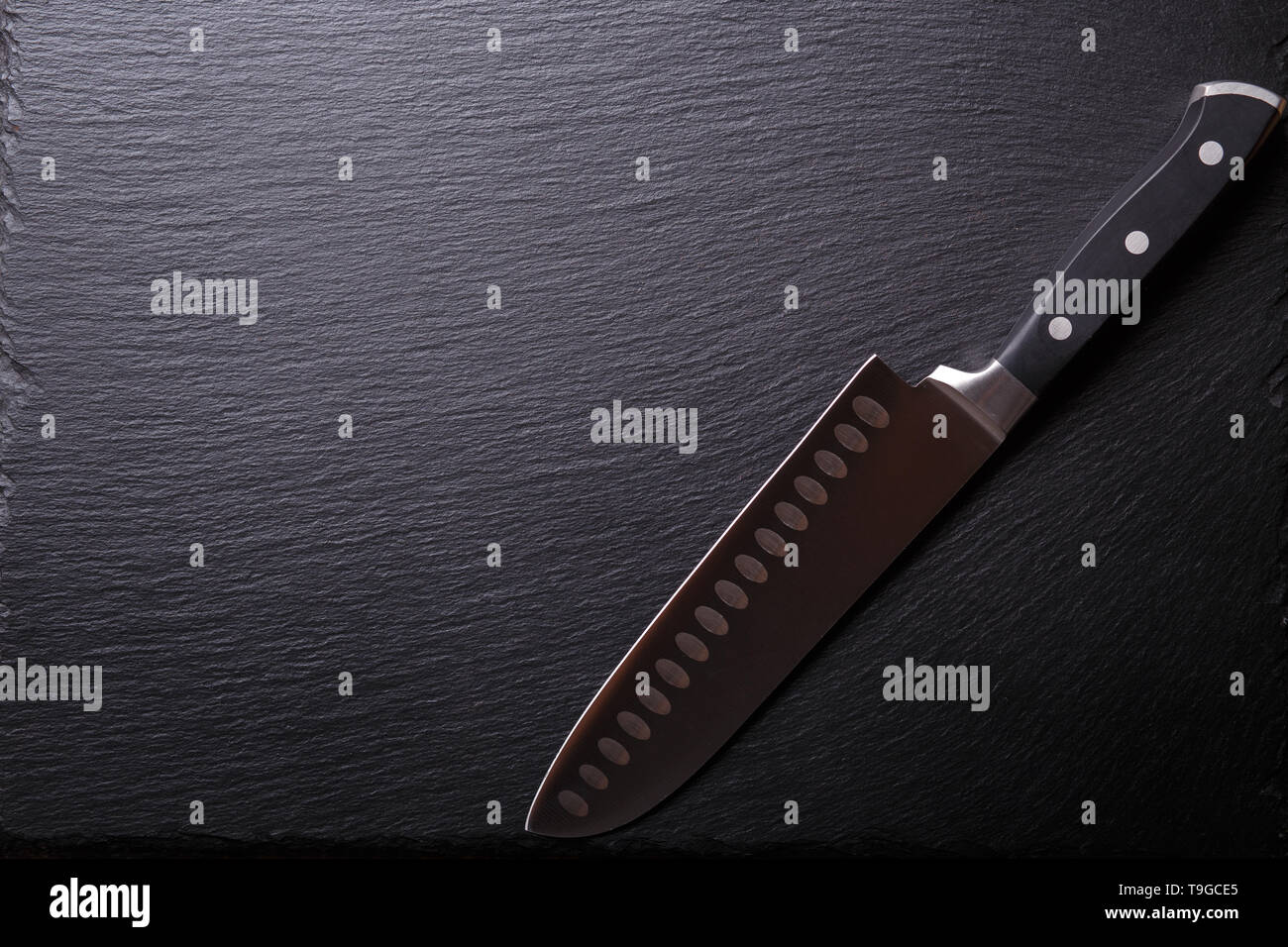 Big chef knife on black slate background with copy space. Menu ...