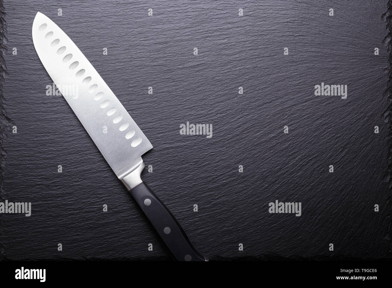 Big chef knife on black slate background with copy space. Menu ...