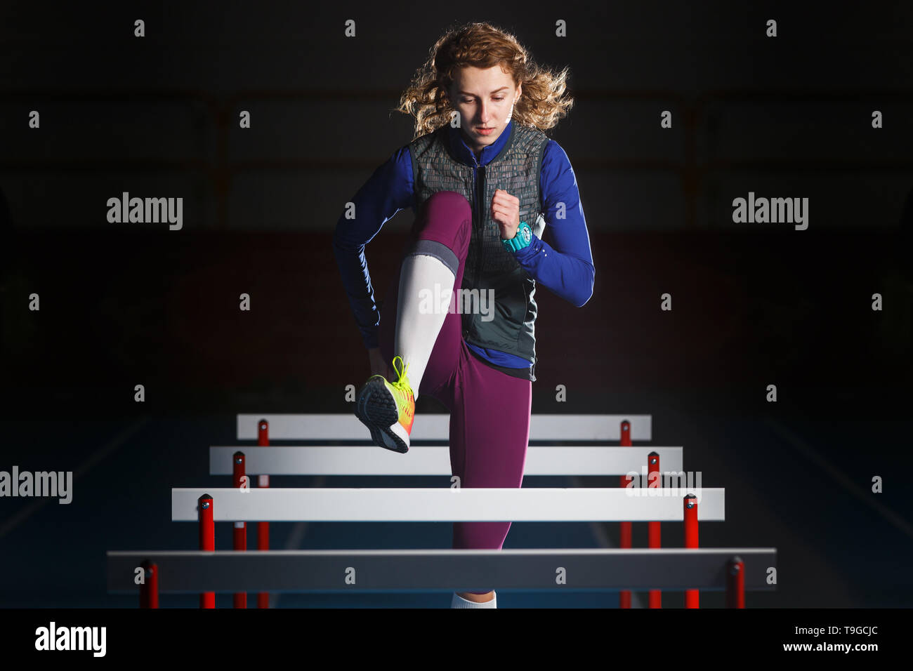 Young professional sportswoman training running with hurdles. Female ...