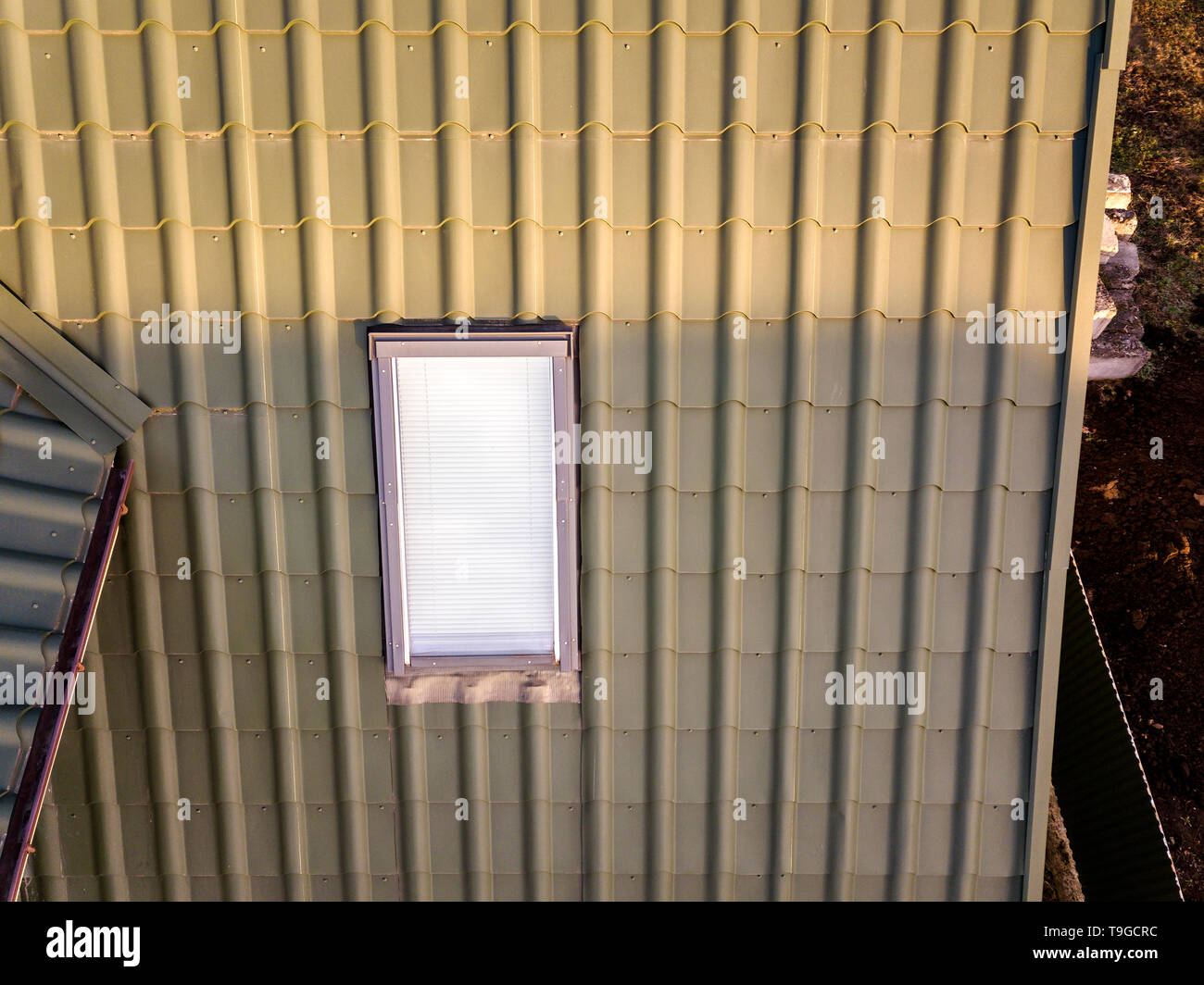 Close-up of new attic plastic window installed in shingled house roof ...