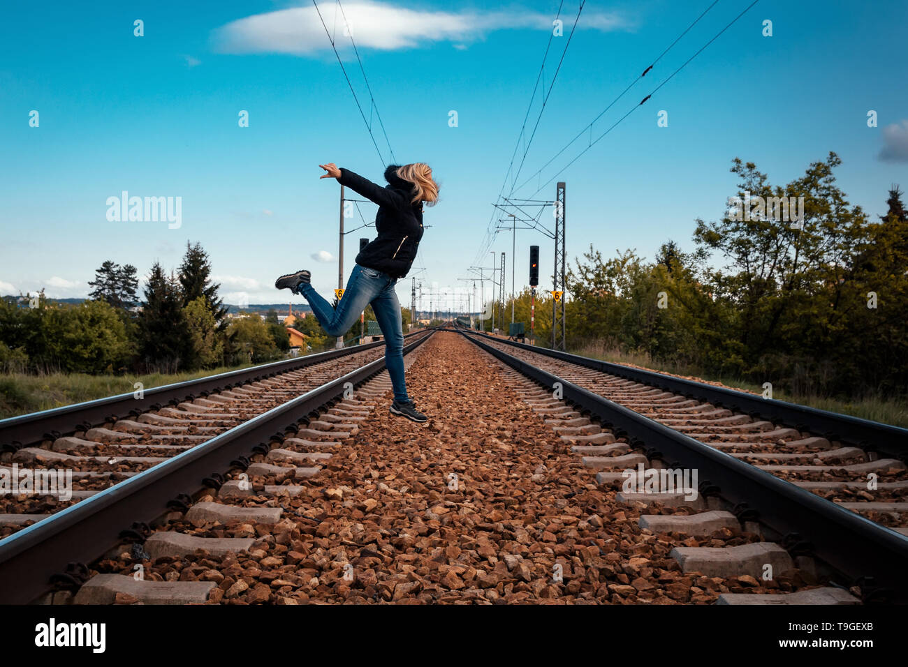 Young woman jump on railroad in black jacket Stock Photo - Alamy