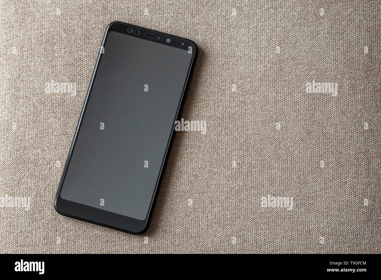 New black modern cellphone isolated on light cloth copy space ...