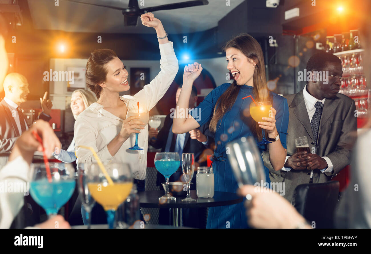 Young glad cheerful smiling attractive women with cocktails having fun ...
