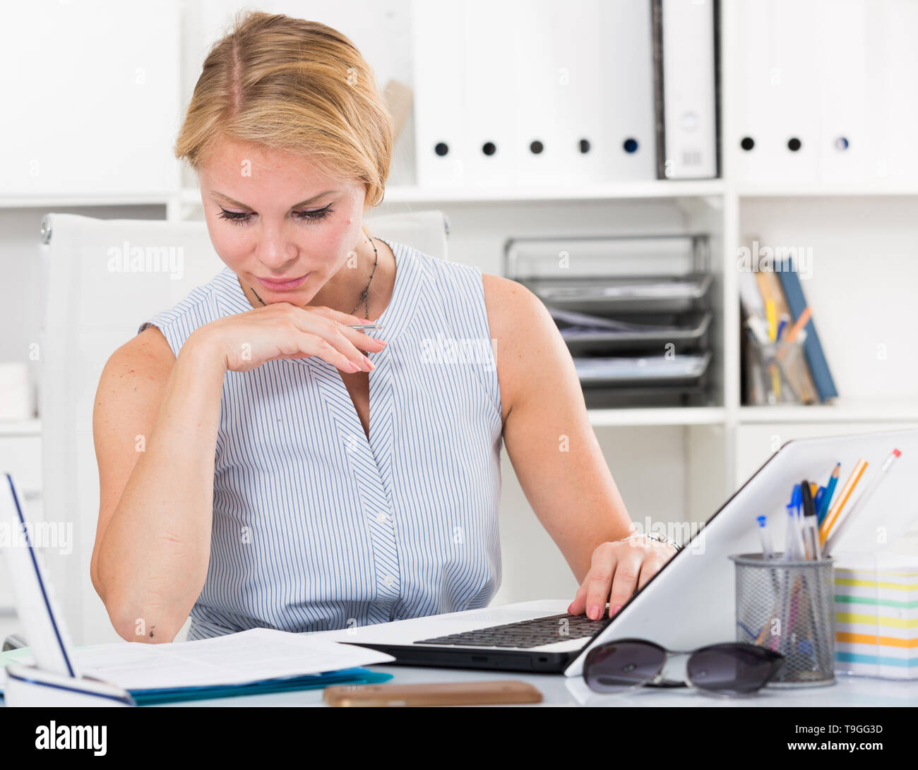 portrait of angry female secretary working with documents and computer ...
