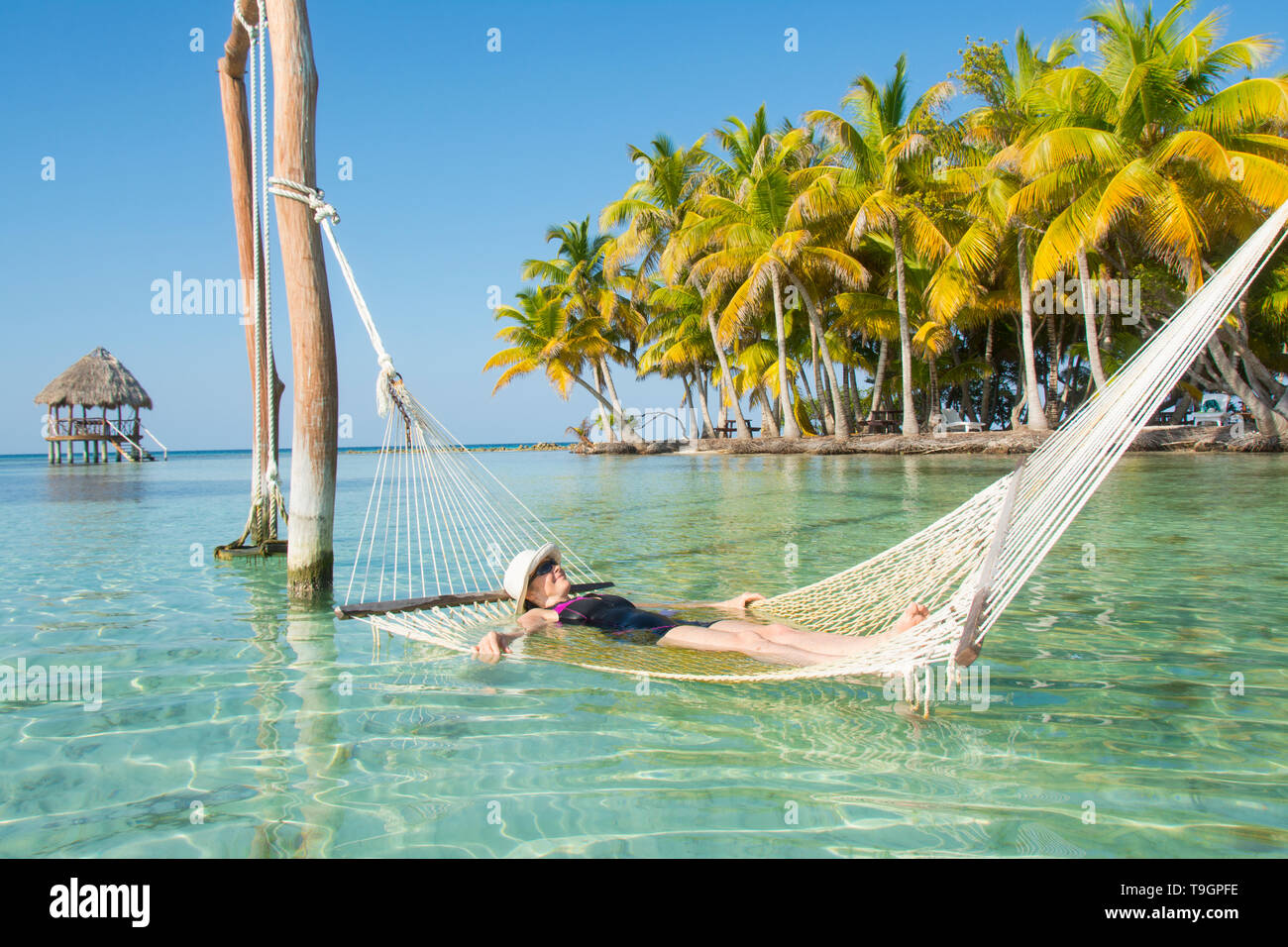 Woman enjoys hammock in tropical waters and Palapa platforms, North ...