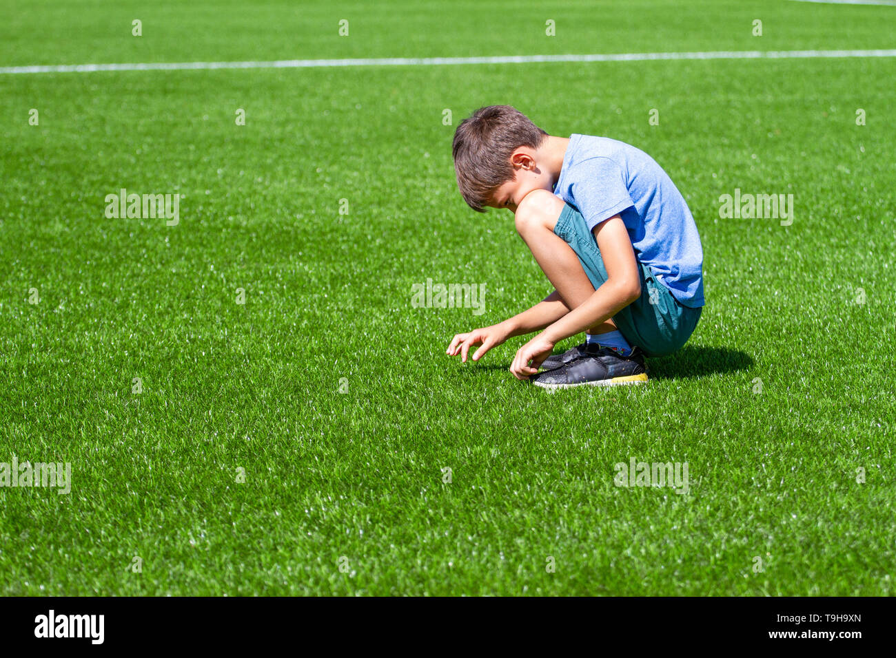 Alone kid sitting on the football field Stock Photo - Alamy