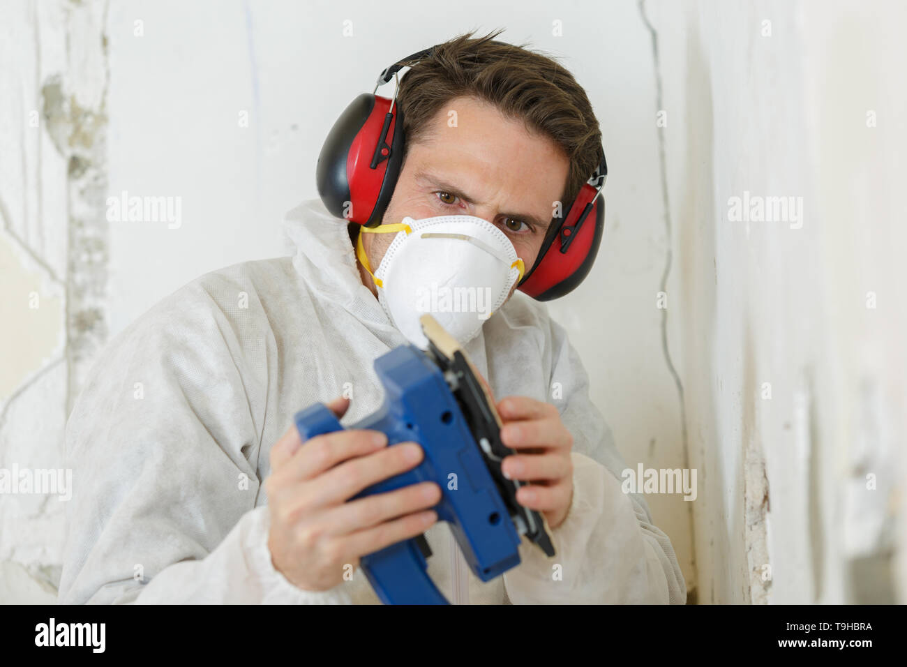 male builder wearing a mask to sand down a wall Stock Photo - Alamy