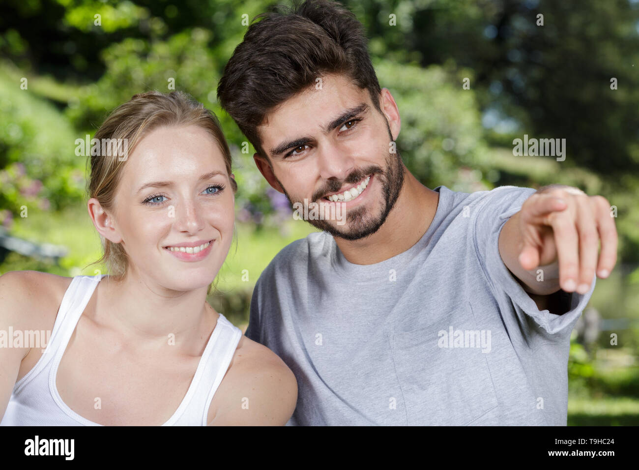 smiling couple pointing away on white background Stock Photo - Alamy