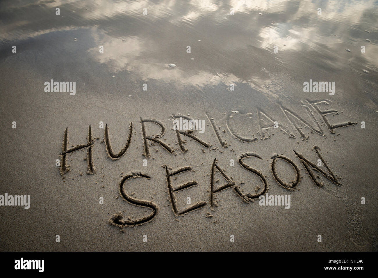 Hurricane Season message handwritten in smooth sand is washed away by ...