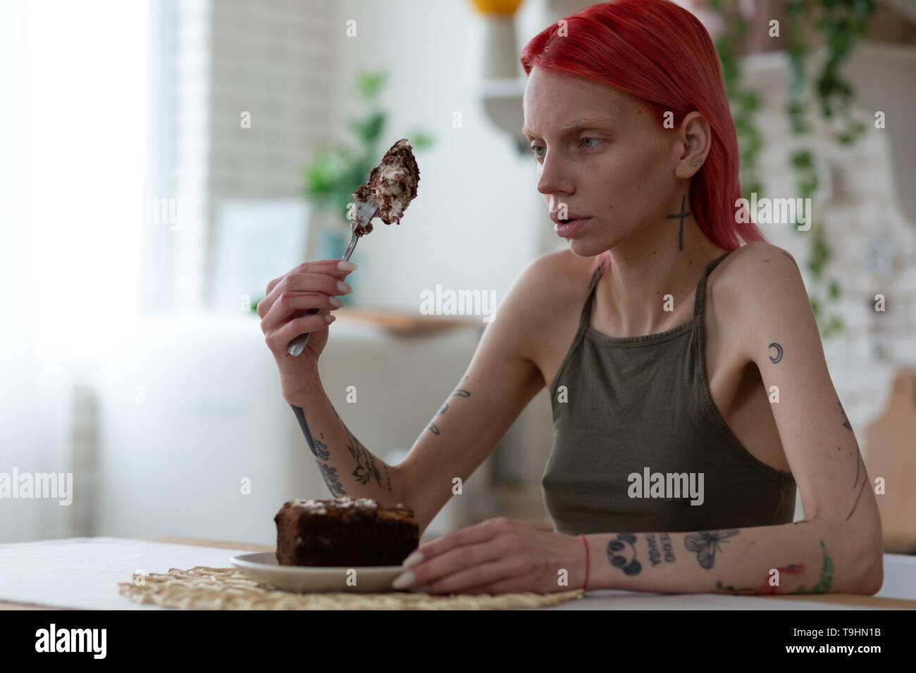 Tattooed skinny woman looking at big piece of dessert Stock Photo - Alamy