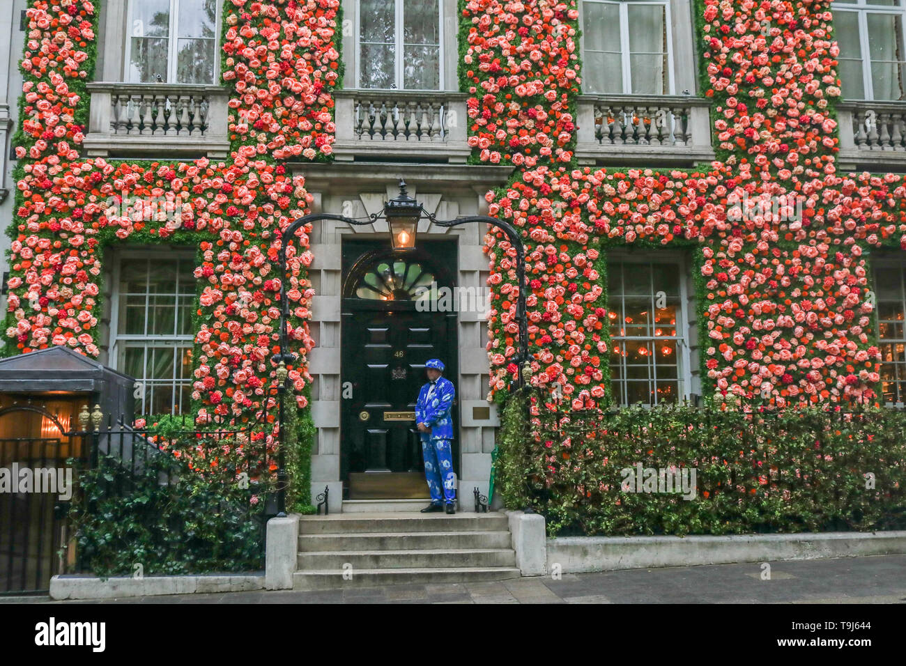London, UK. 19th May 2019. A doorman in a colourful suit stands in ...
