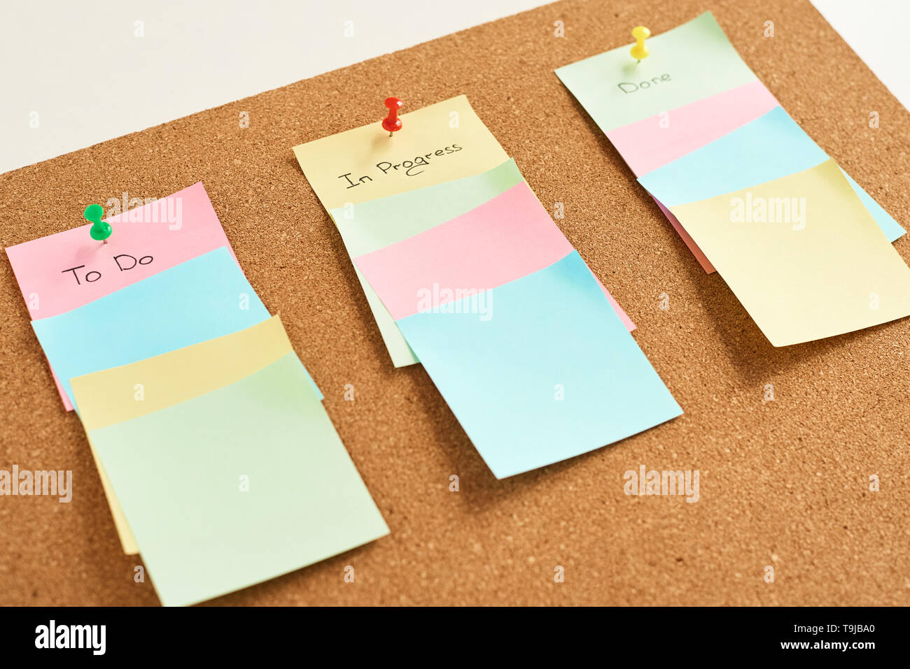 Colored paper stickers with words to do, in progress and done on cork ...