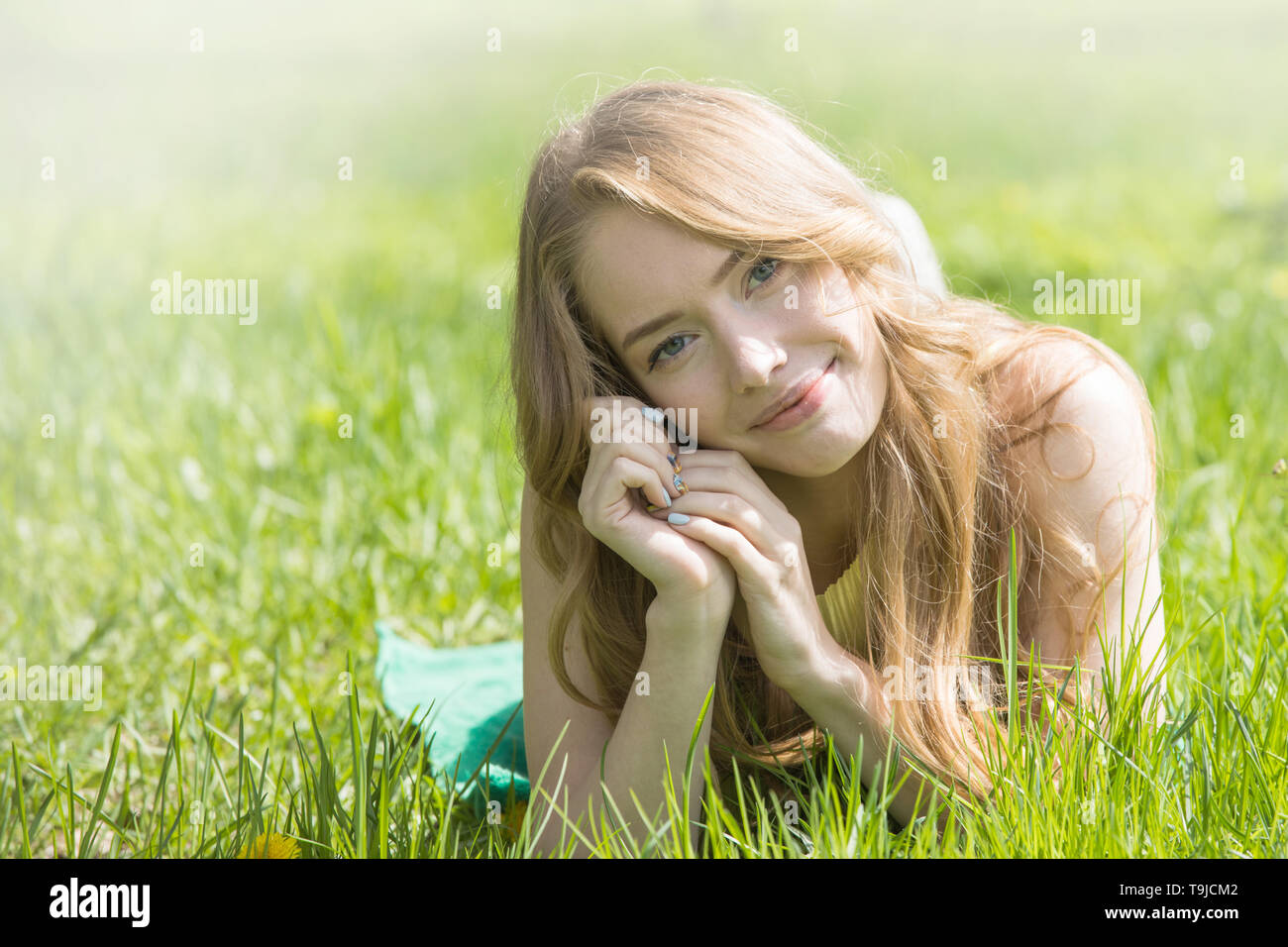 Blonde pretty girl laying on the grass in spring park and smiling Stock ...