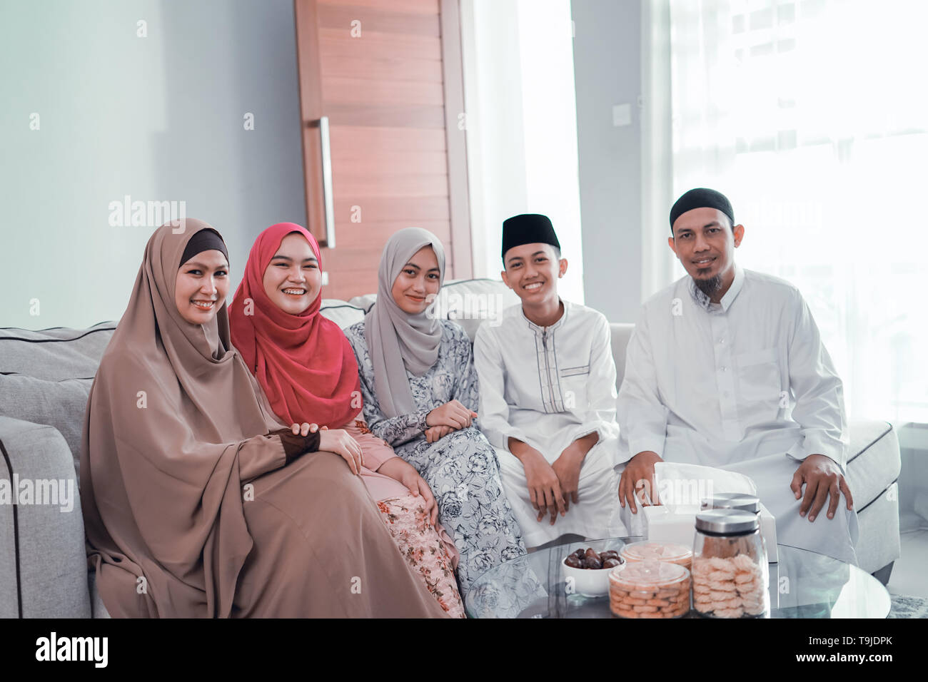 portrait of asian happy muslim family sitting on the couch at home ...