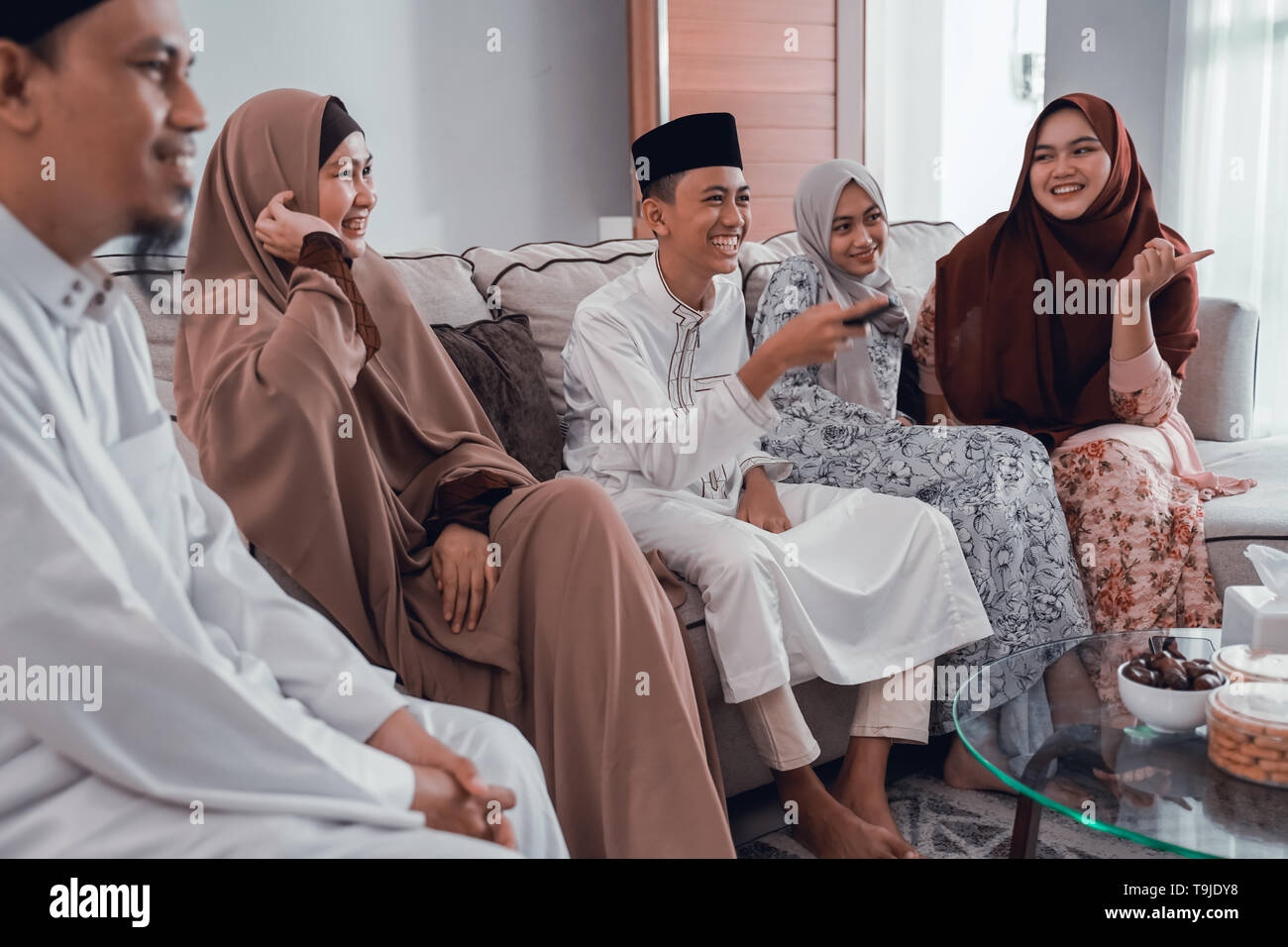 happy muslim family watching tv together at home livingroom Stock Photo ...