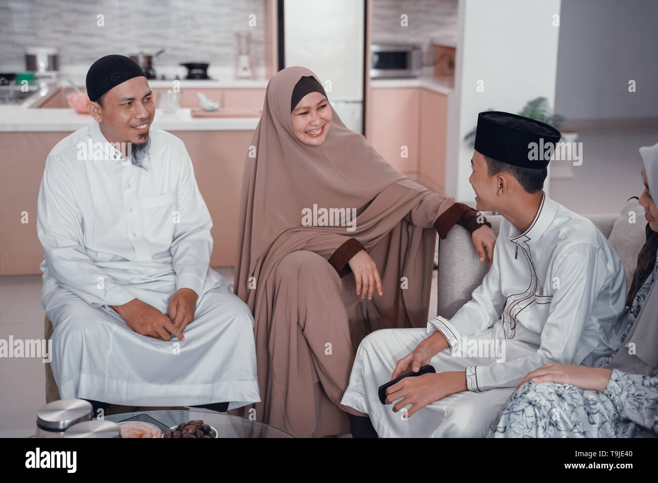 asian muslim people talk to each other at home together in livingroom ...