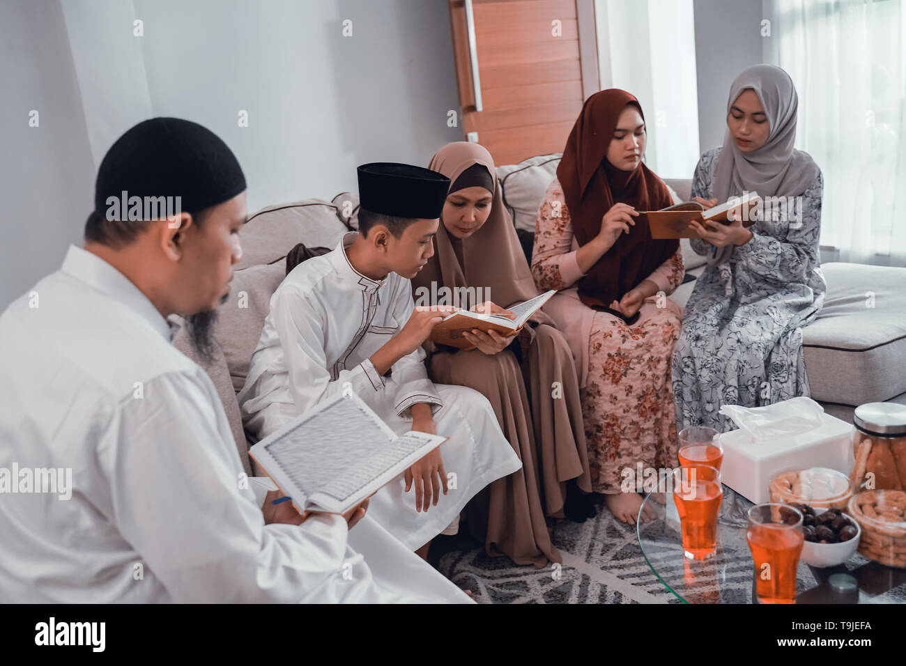 portrait of muslim family reading quran together in livingroom Stock ...
