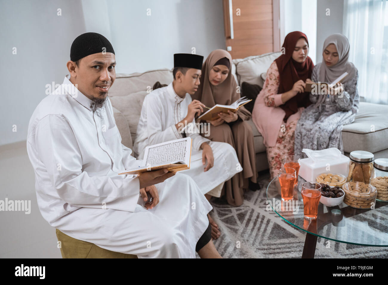 portrait of muslim family reading quran together in livingroom Stock ...