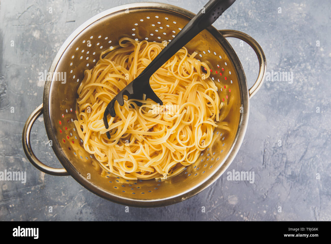 Italian pasta linguine in a metal colander on grey background. Top view ...